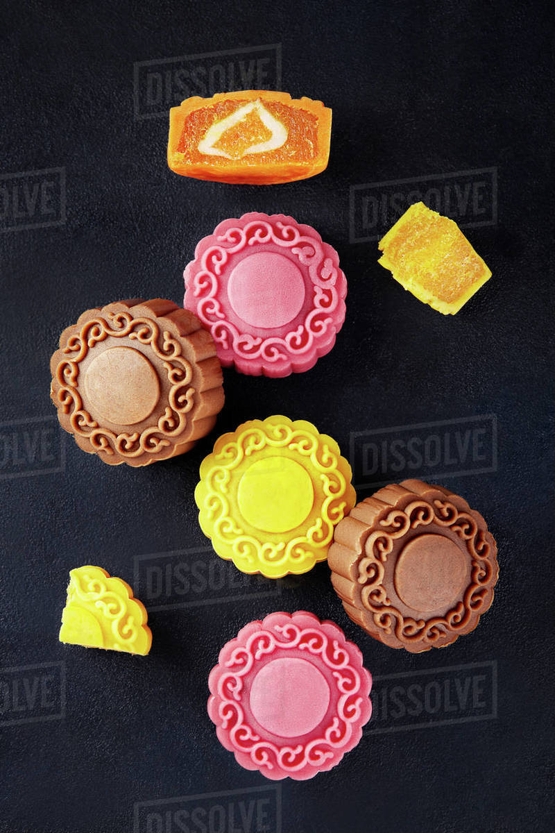 Overhead view of assorted multi coloured mooncakes on a black ...