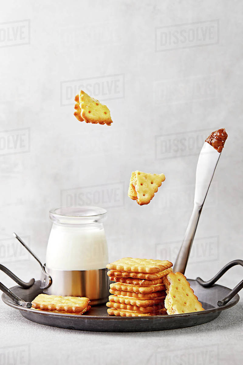 Stack of crackers and milk on a metal tray with a caramel covered knife ...