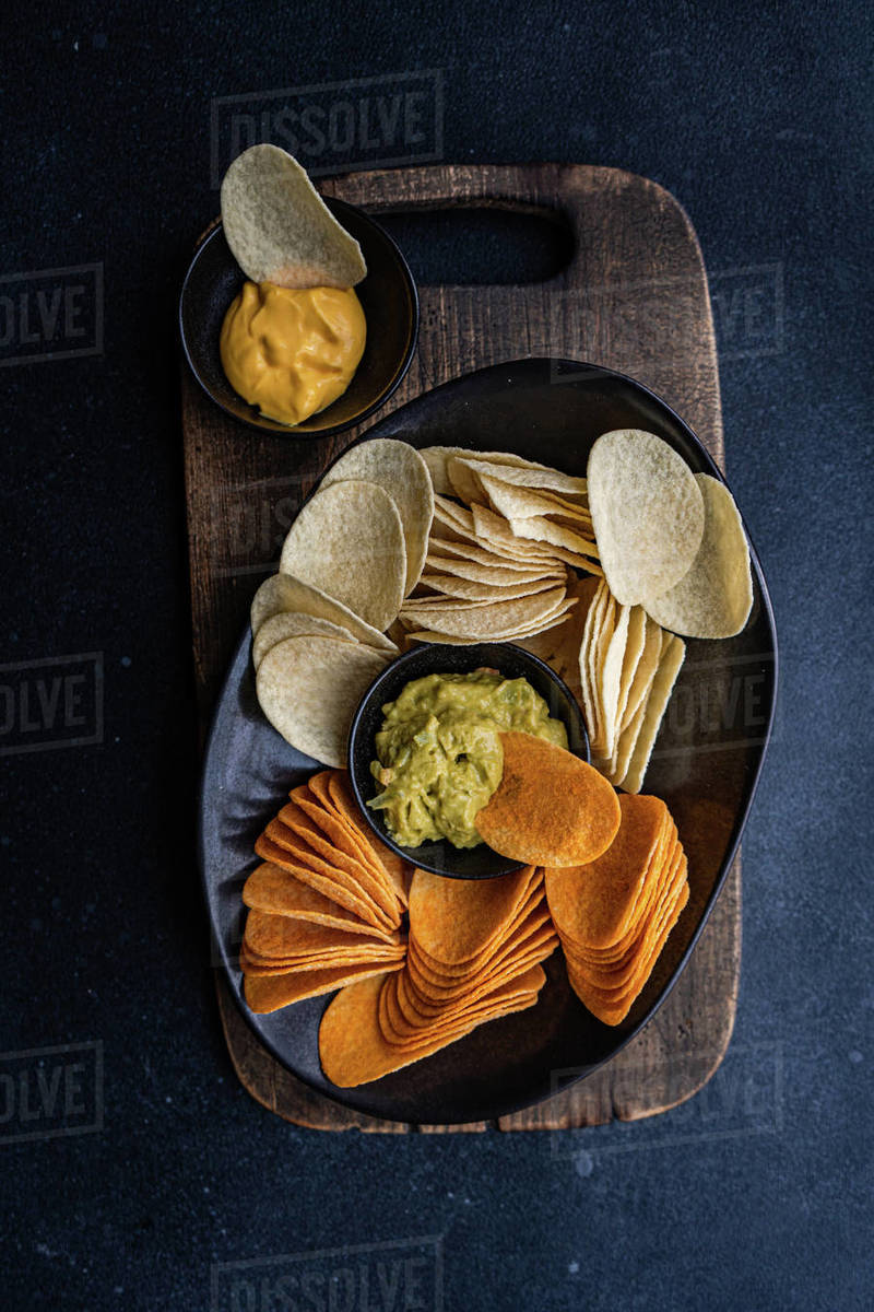 Overhead view of a plate of assorted crisps with guacamole and cheese ...