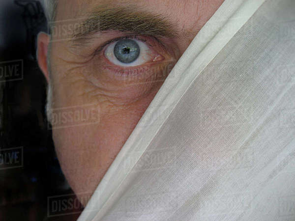 Close-up portrait of a man's face partially hidden behind a curtain ...