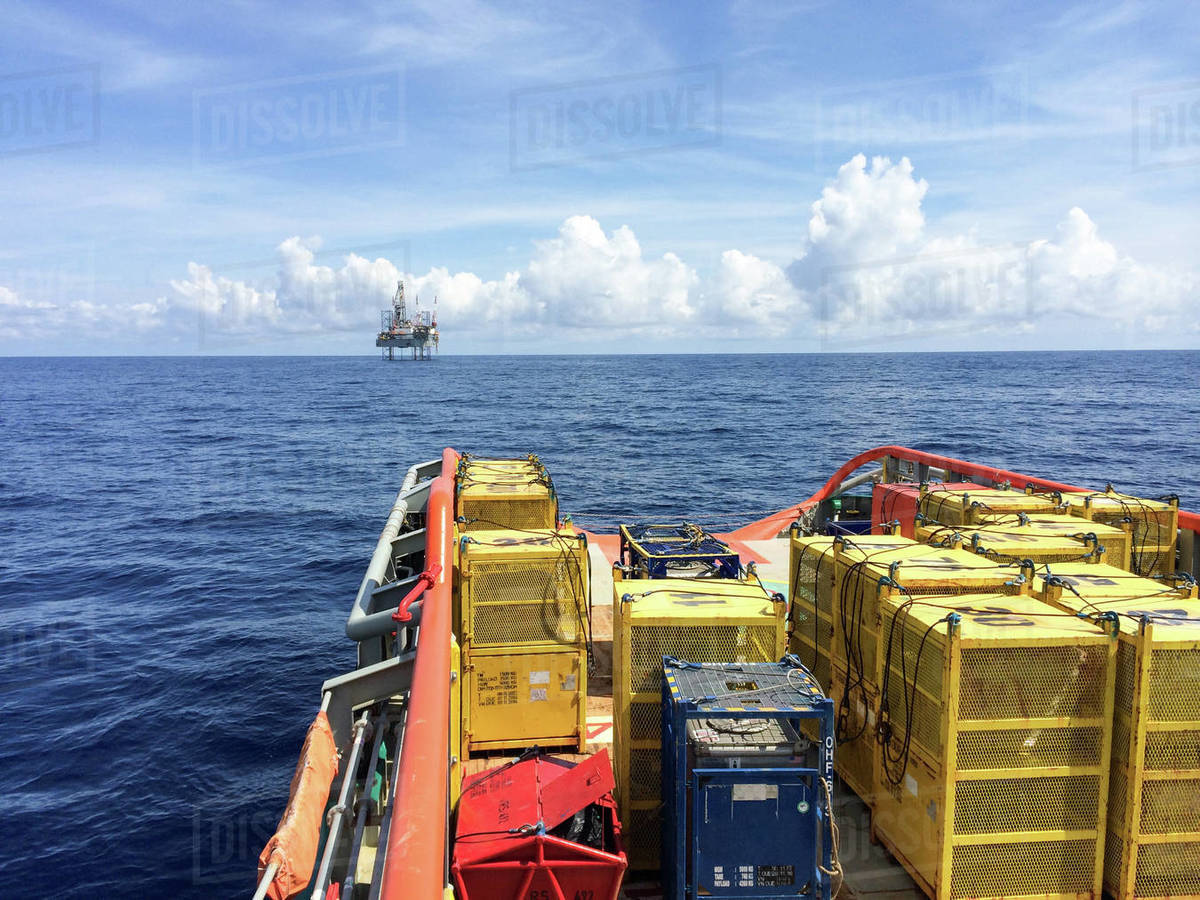 Oil rig support vessel transporting cargo to oil rig seen on horizon ...