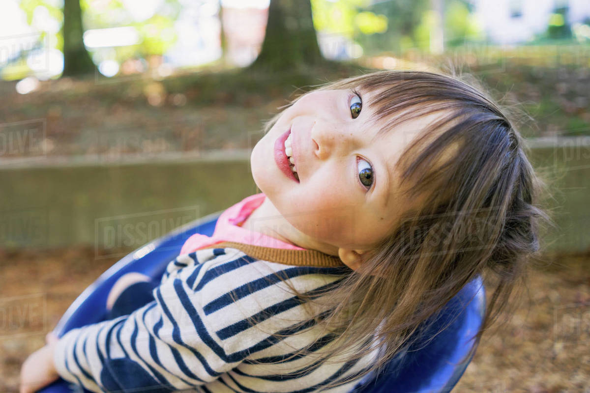 Smiling girl in playground looking over her shoulder - Royalty-free ...