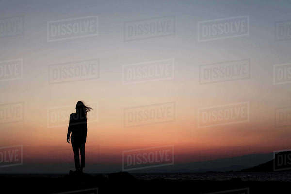Silhouette of a woman standing outdoors at sunset - Royalty-free Stock ...