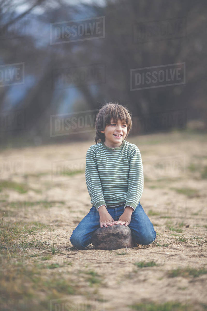 Smiling boy sitting on a rock - Stock Photo - Dissolve