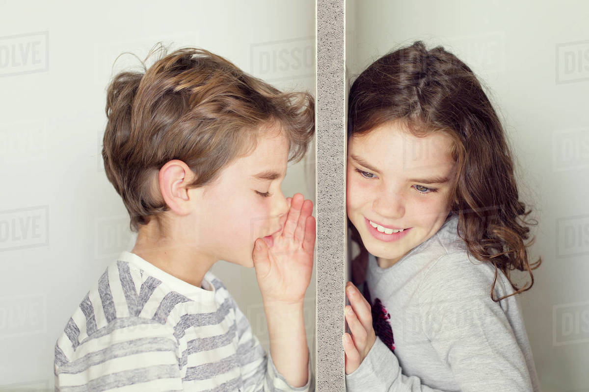 Boy whispering a secret to a girl - Royalty-free Stock Photo | Dissolve