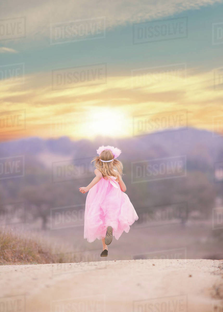 Girl wearing pink dress running down road - Stock Photo - Dissolve