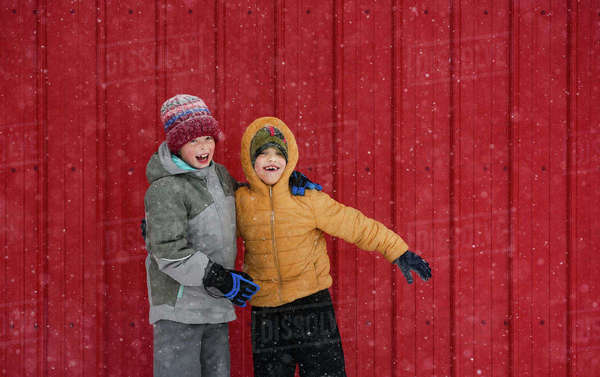 Two happy children messing about in front of a red house, USA - Royalty ...