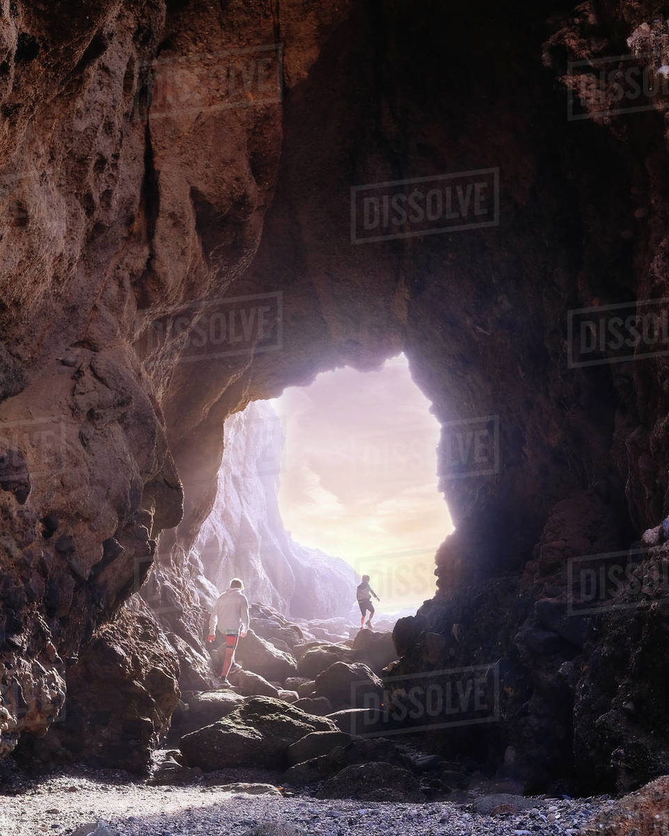 Two boys walking through a cave at sunset, Laguna Beach, California ...