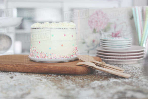 Layer cake with buttercream frosting and sprinkles on a table with a ...