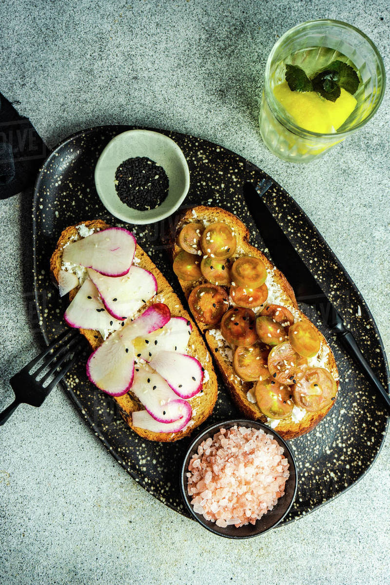 Overhead view of two wholegrain toasts with cheese, tomato, radish ...