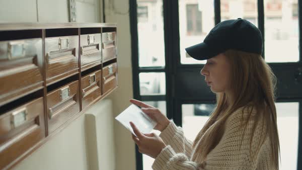 Smiling girl taking junk mail out the posting box - Stock Video Footage ...