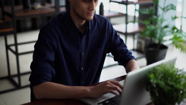 Serious focused young businessman works on desktop. Handsome man using ...