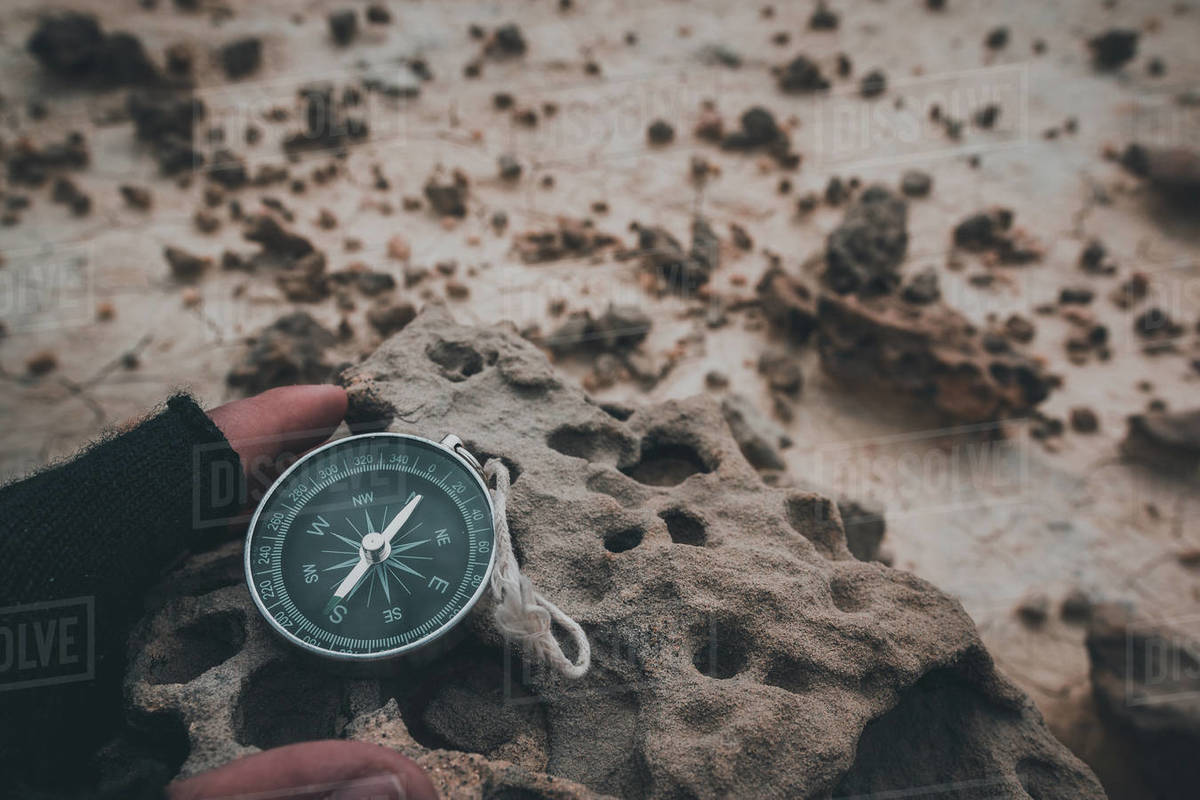 Compass in hand on dry desert area - Stock Photo - Dissolve