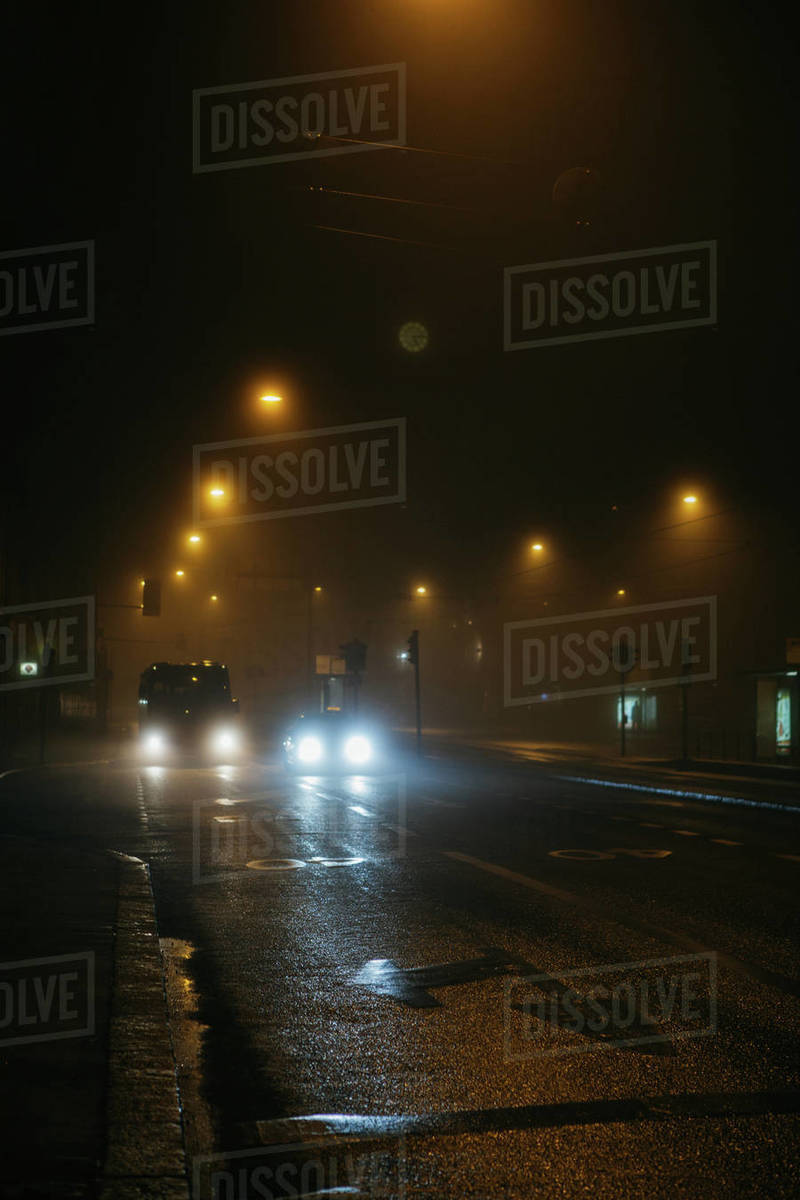 Hazy city street with cars glowing and driving in thick fog in night ...