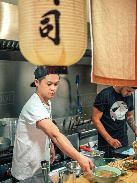 Multiracial men cooking Japanese dish called ramen in Asian restaurant ...