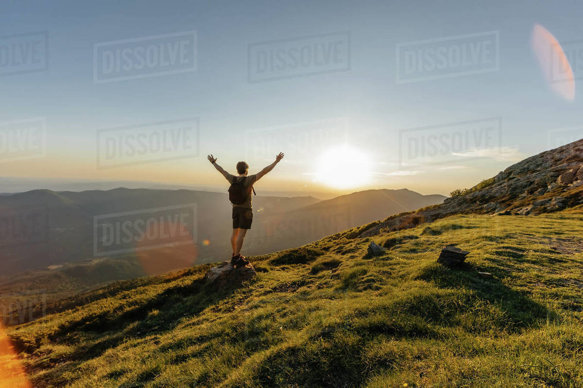Back view of young man with back pack contemplating amazing mountain ...