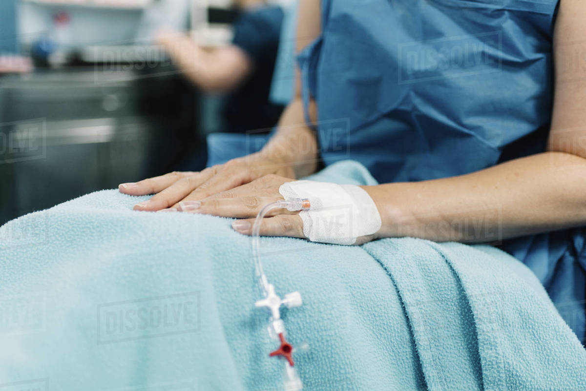 Crop female patient sitting with covered legs and intravenous fluid ...