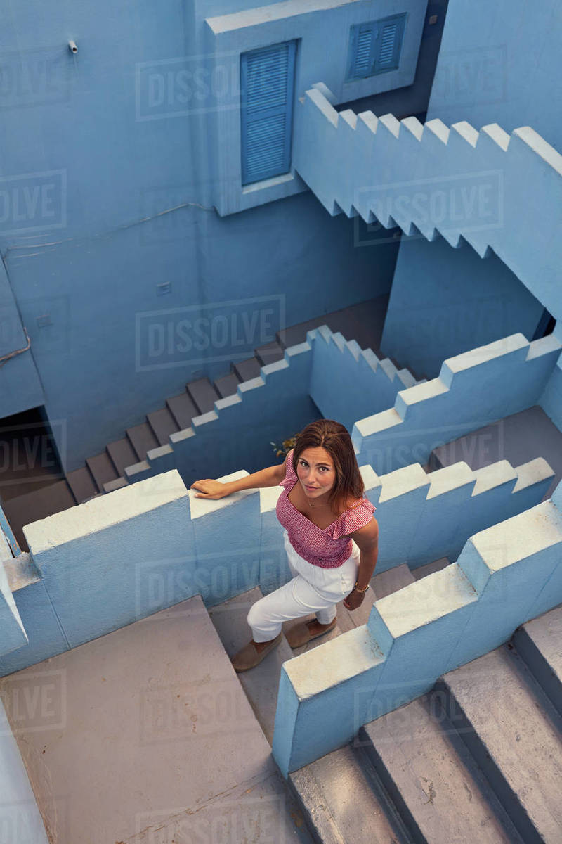 From above top view of young woman walking upstairs on modern blue ...