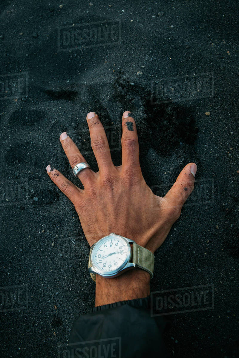 Hand of crop person with hand watch on big pile of black sand in ...