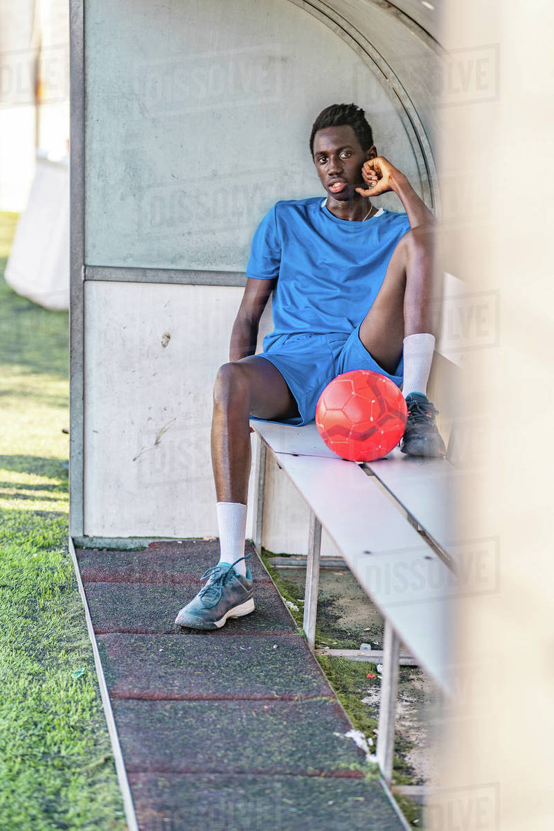 Black football player resting on bench - Stock Photo - Dissolve