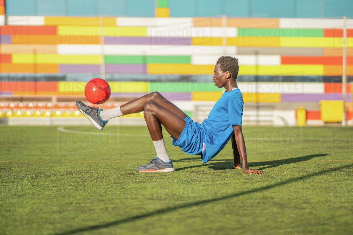 Side view of ethnic football player leaning back and juggling ball on ...
