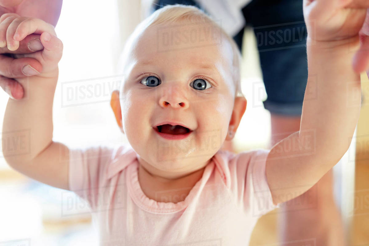 Cute baby with blond hair and light blue sky looking at camera with ...