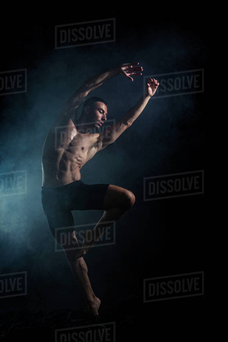 Full body of faceless tanned sporty shirtless dancer in shorts raising ...