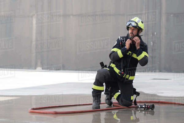 Contemplative unshaven firefighter in uniform with stripes and ...