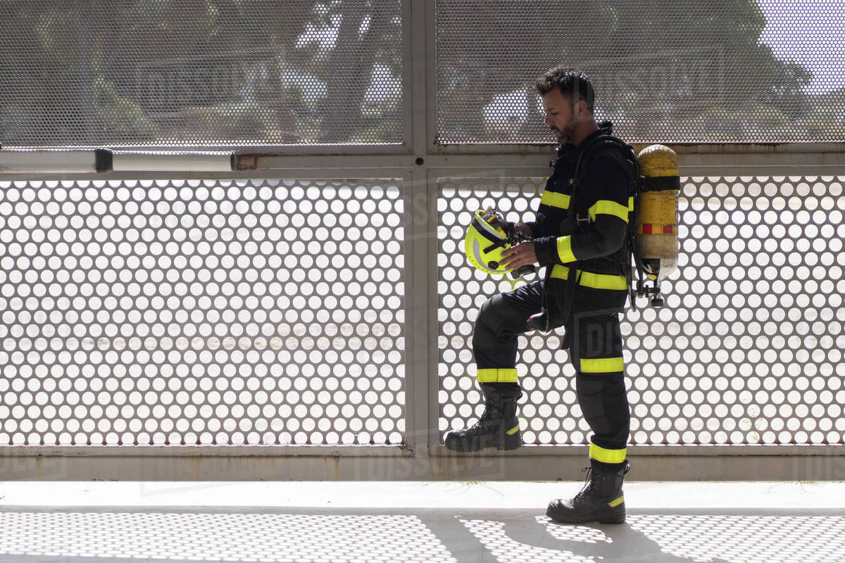 Side view of firefighter in striped uniform with extinguisher and ...