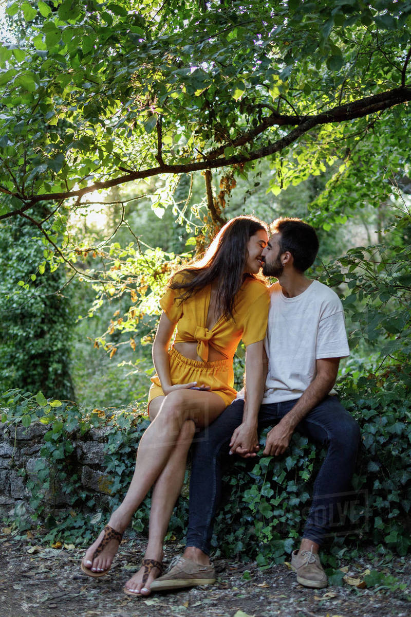 Full body of young stylish couple in casual clothes kissing while ...