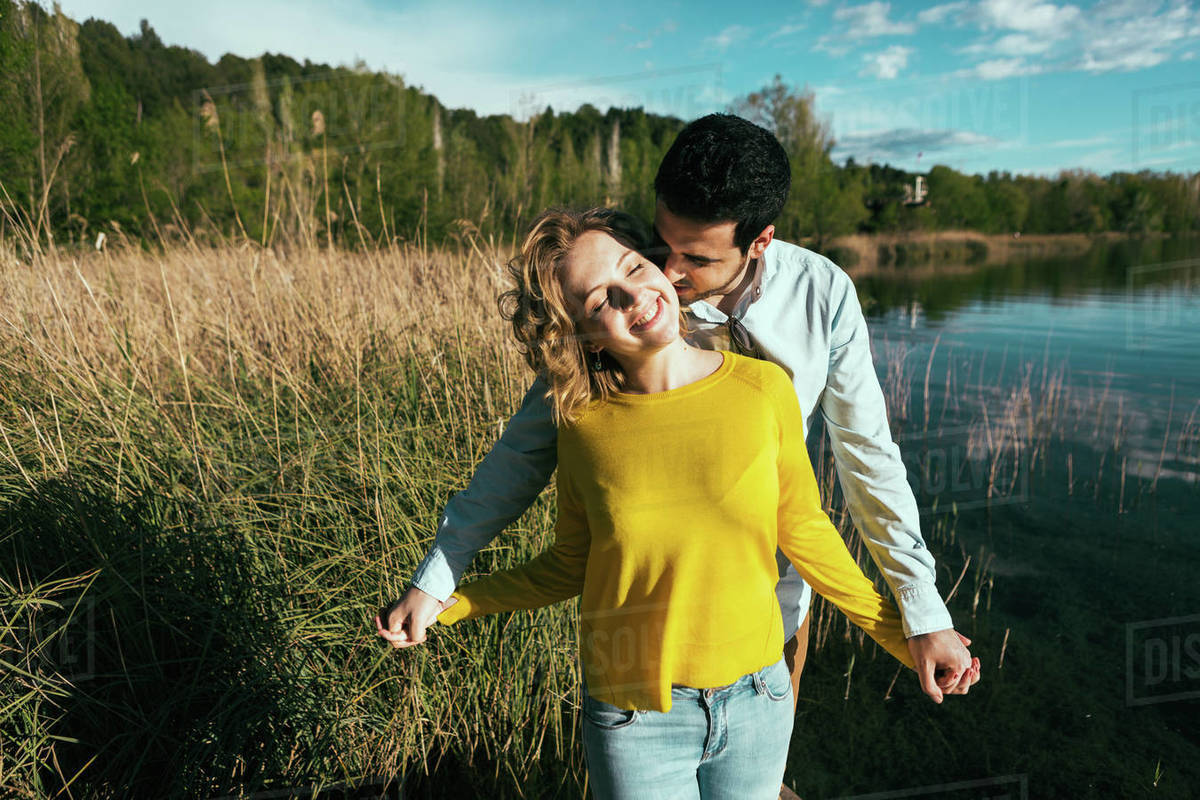 Delighted girlfriend and calm boyfriend hugging while standing together ...