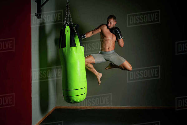 Full length of enduring shirtless male kickboxer in boxing gloves ...