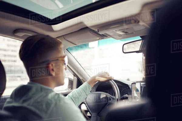 Back view of unrecognizable focused male driver driving a luxury car ...