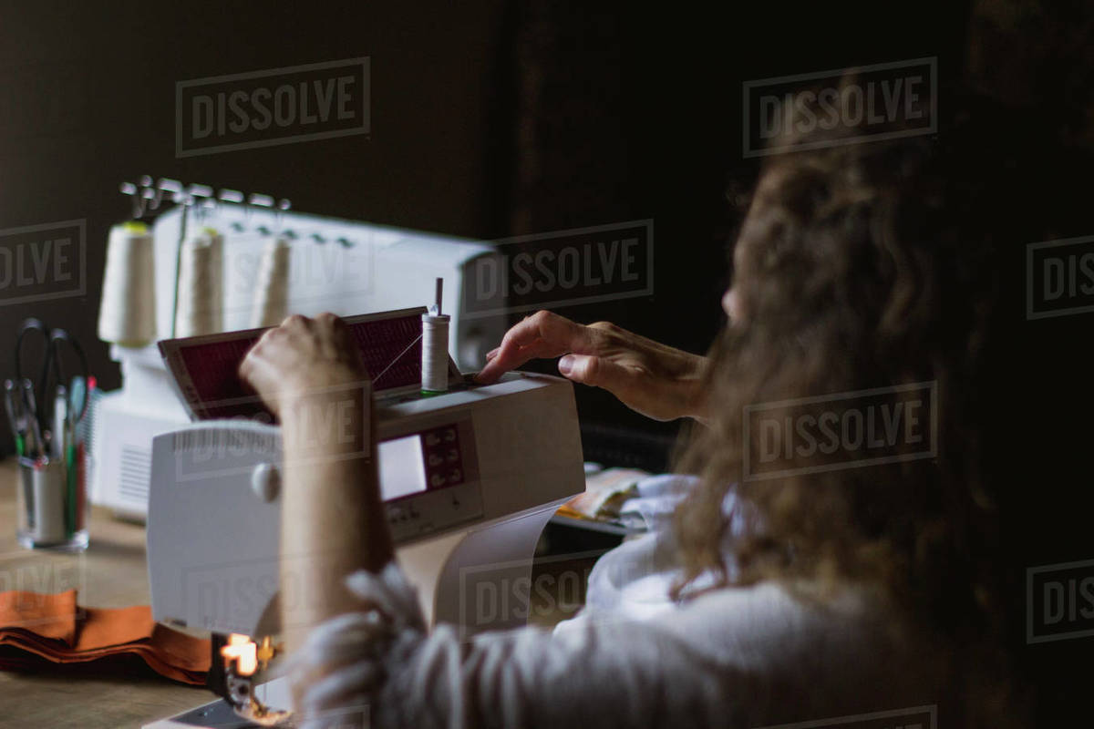 Back view of anonymous crop woman using sewing machine making clothes ...