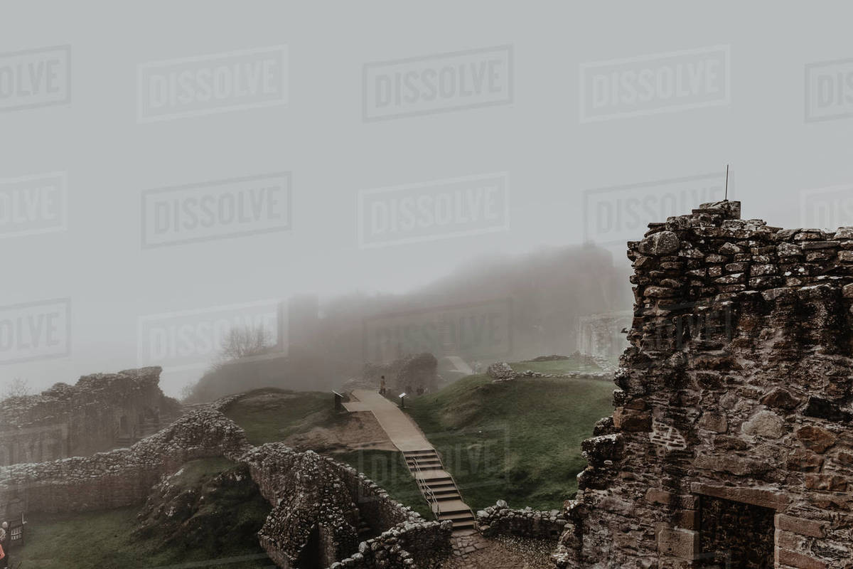 Destroyed old stone castle with fog with walls and stairs with tower on ...