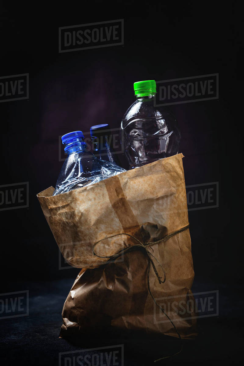 Dirty paper sack with discarded plastic bottles placed on black ...