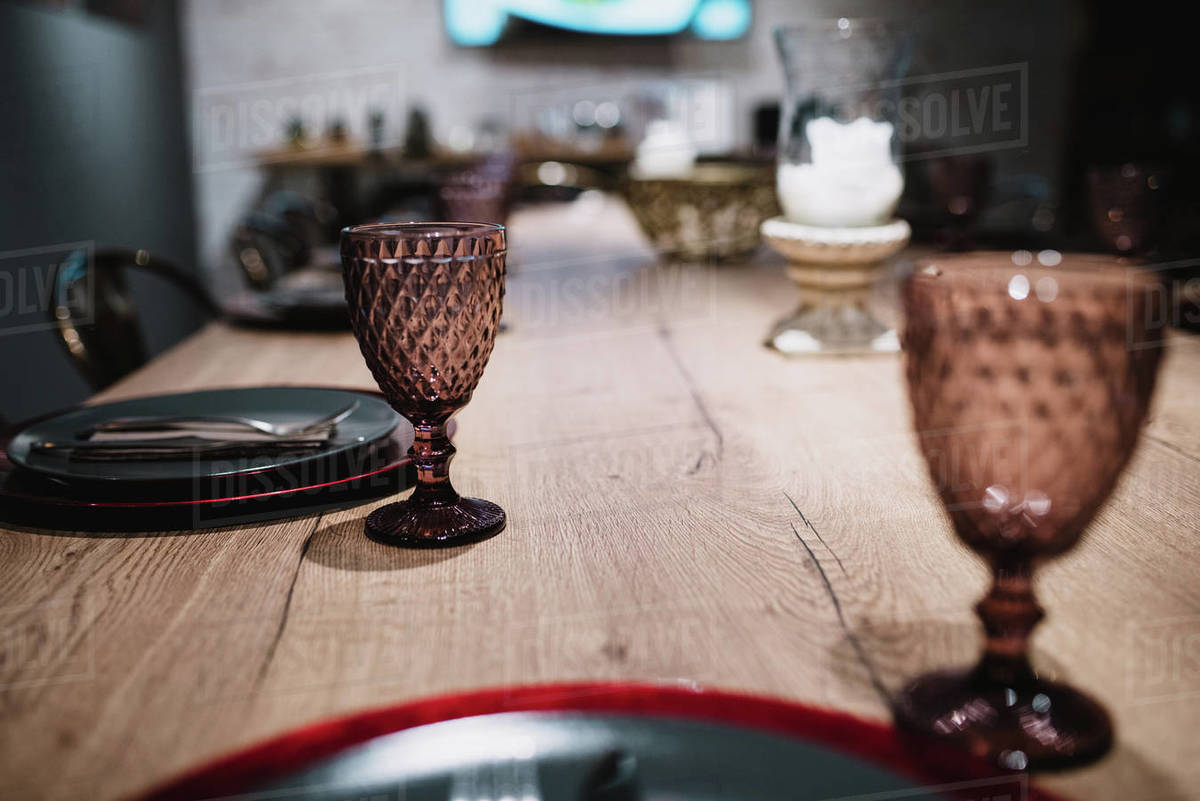 Glass goblets placed on wooden table near plates and silverware in ...