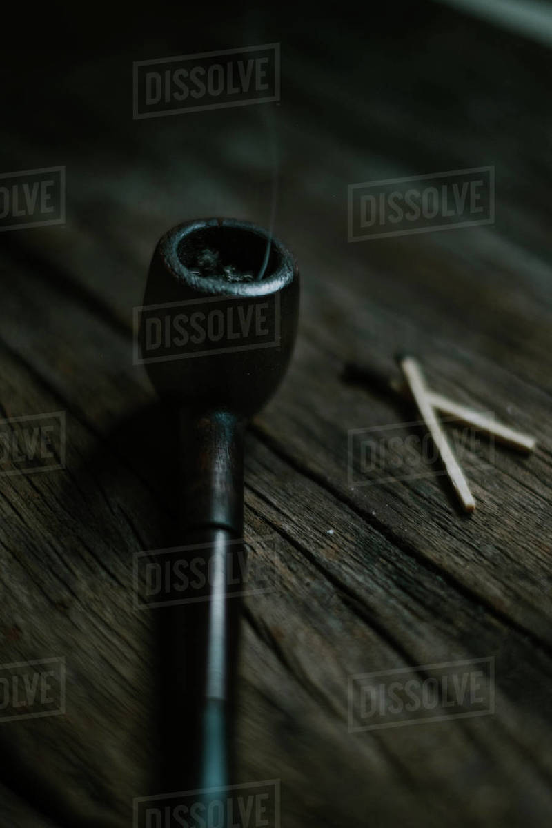 From above old fashioned smoking pipe and matches placed on rough ...