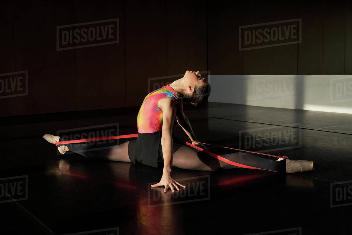 Side view of professional ballet dancer lying down on the floor with ...