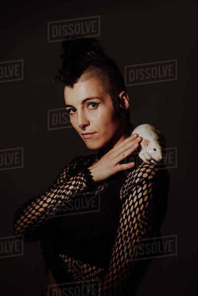Confident woman with mohawk carrying white rat on shoulder and looking ...