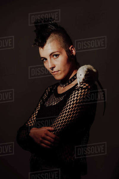 Confident woman with mohawk carrying white rat on shoulder and looking ...