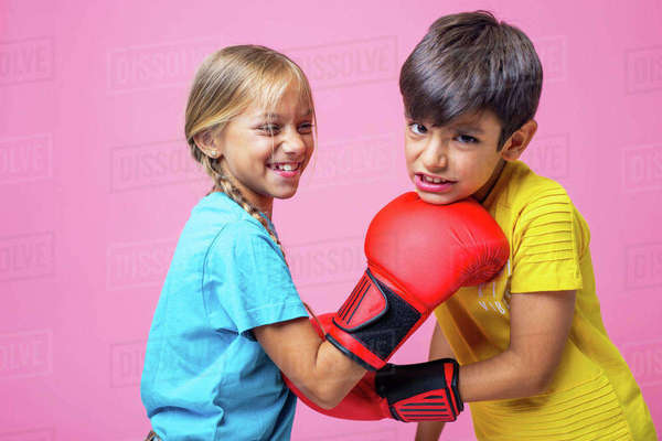Side view of cheerful little boy and girl hitting each other in jaw and ...