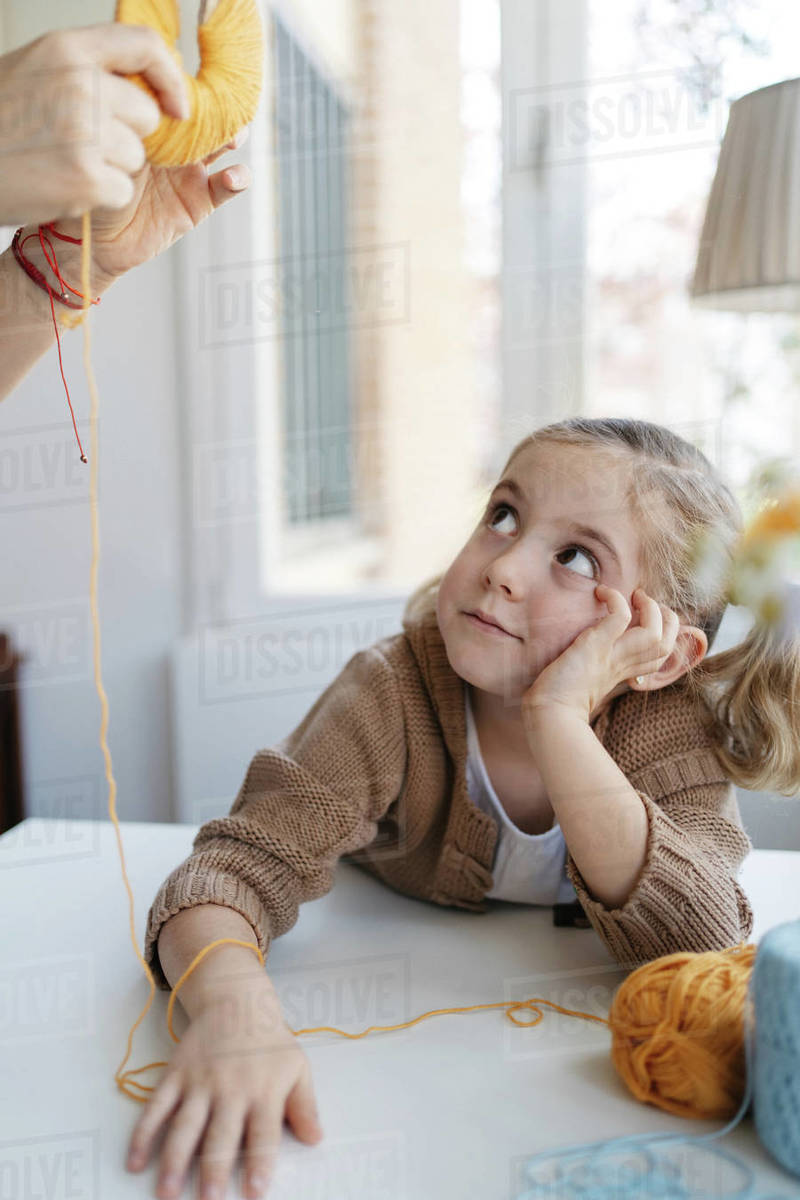 Cute blond girl in warm sweater leaning on hand and looking at ...