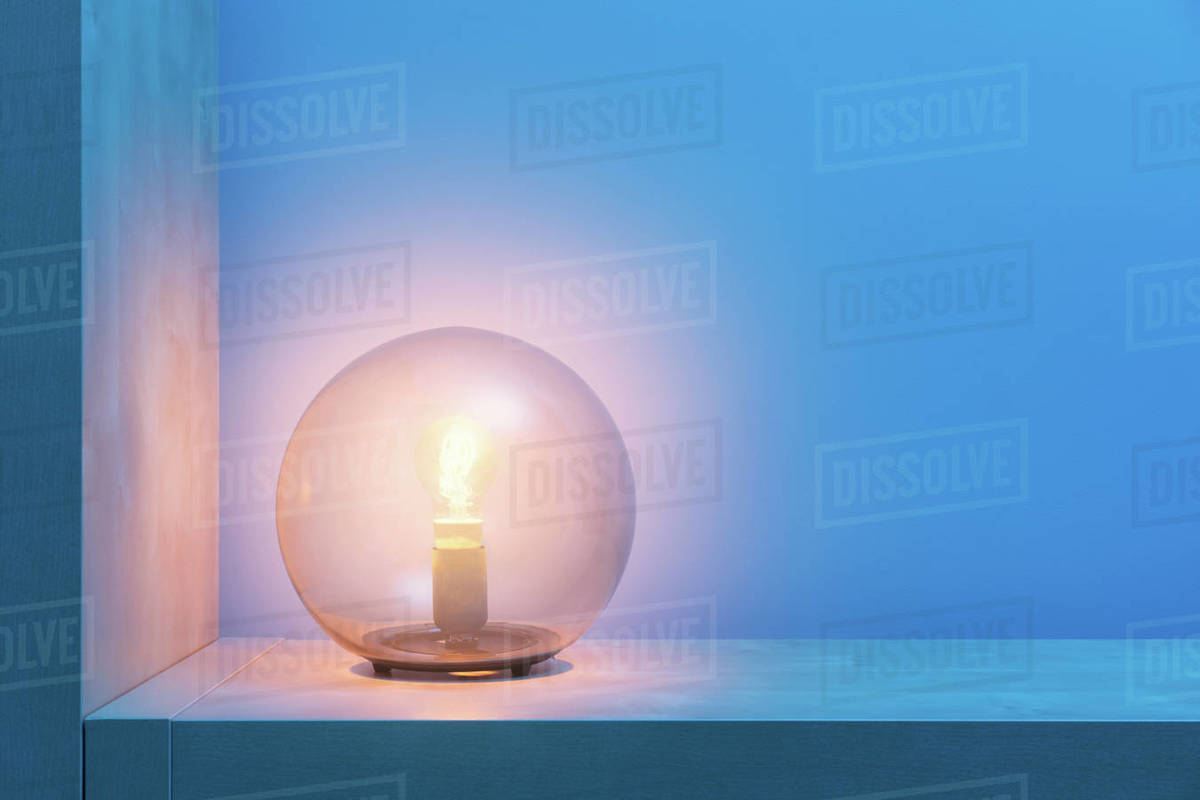Stylish round lamp with glowing yellow light inside of glass ball ...