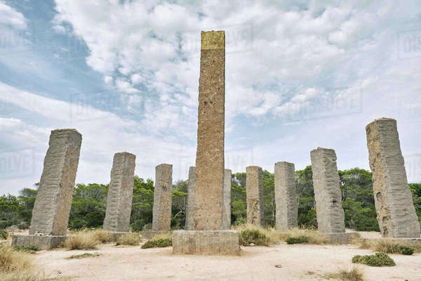 Aged stone columns located on sandy territory surrounded by green ...
