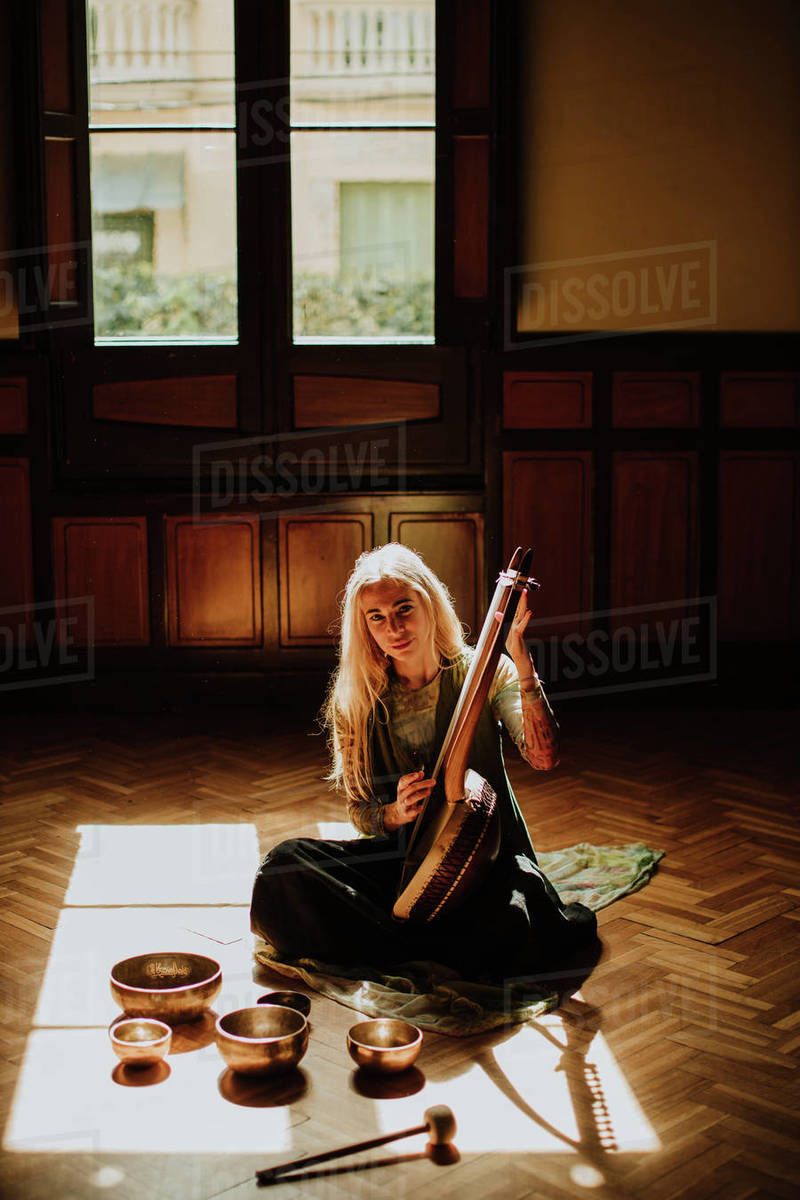 Woman playing lyre near tibetan bowls - Royalty-free Stock Photo | Dissolve