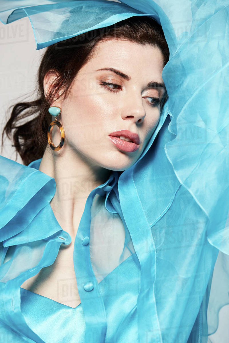 Alluring model wearing transparent blue blouse and covering face with ...