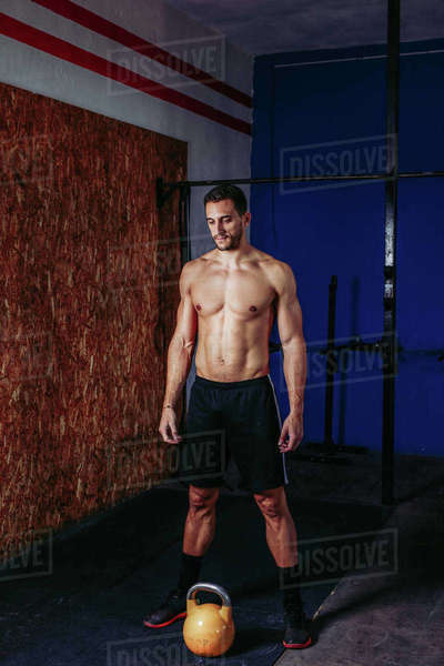 Determined male athlete working hard in gym while doing kettlebell ...