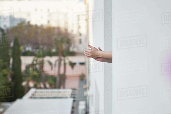 View of crop person clapping hands out window while chilling on balcony ...