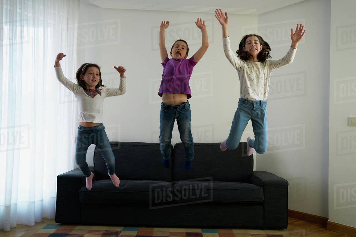 Group of cheerful kids jumping from sofa in living room - Royalty-free ...